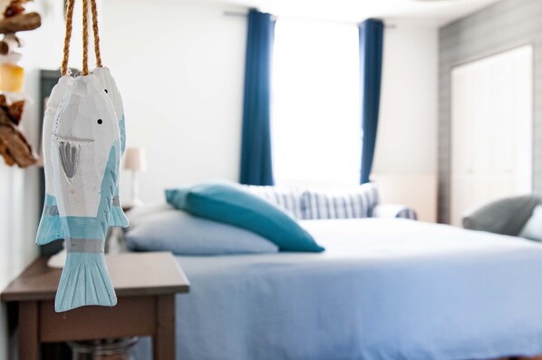 Quarto de hotel com cama, cortinas azuis e um objeto pendurado.