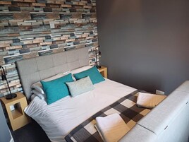 Um quarto moderno com uma cama, cabeceira, mesa de cabeceira e abajur.