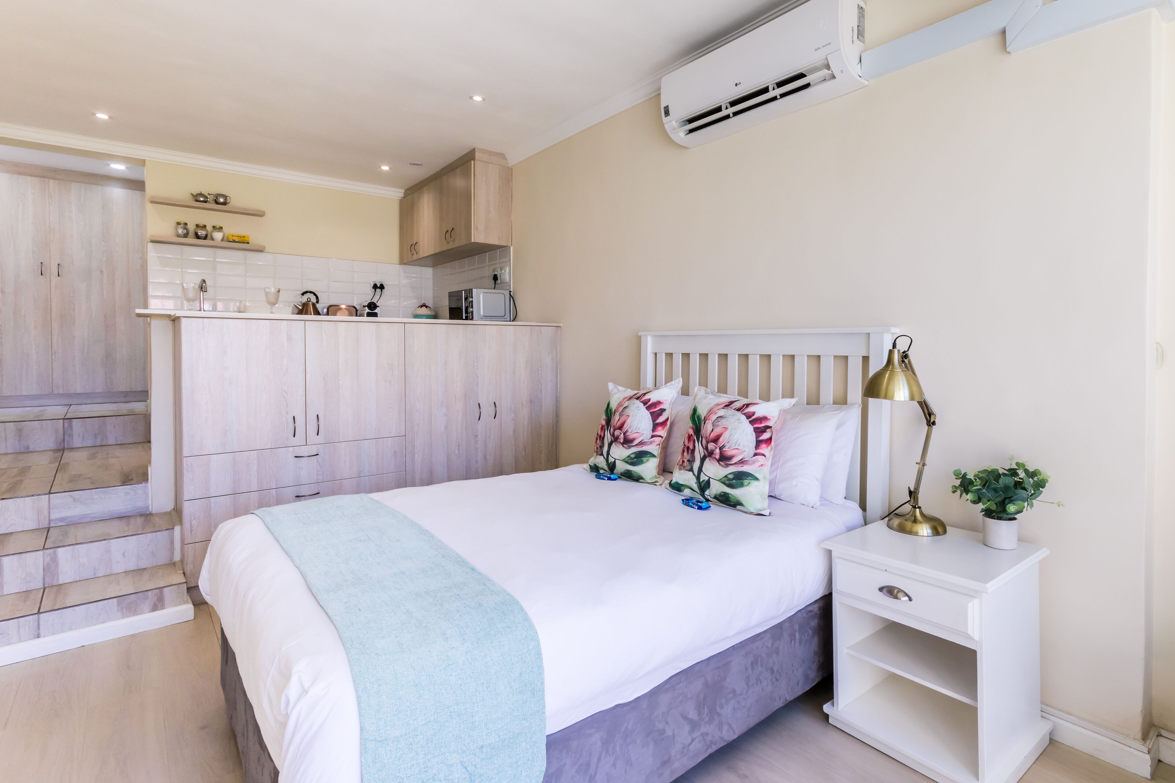 Quarto com uma cama, mesa de cabeceira e vista para a cozinha.