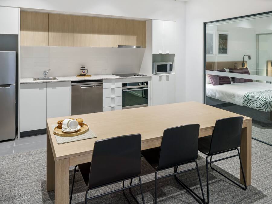 Uma cozinha moderna com mesa e cadeiras de madeira, micro-ondas e geladeira.