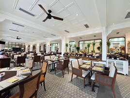 Um restaurante amplo com pé-direito alto, várias mesas e diversos tipos de assentos.