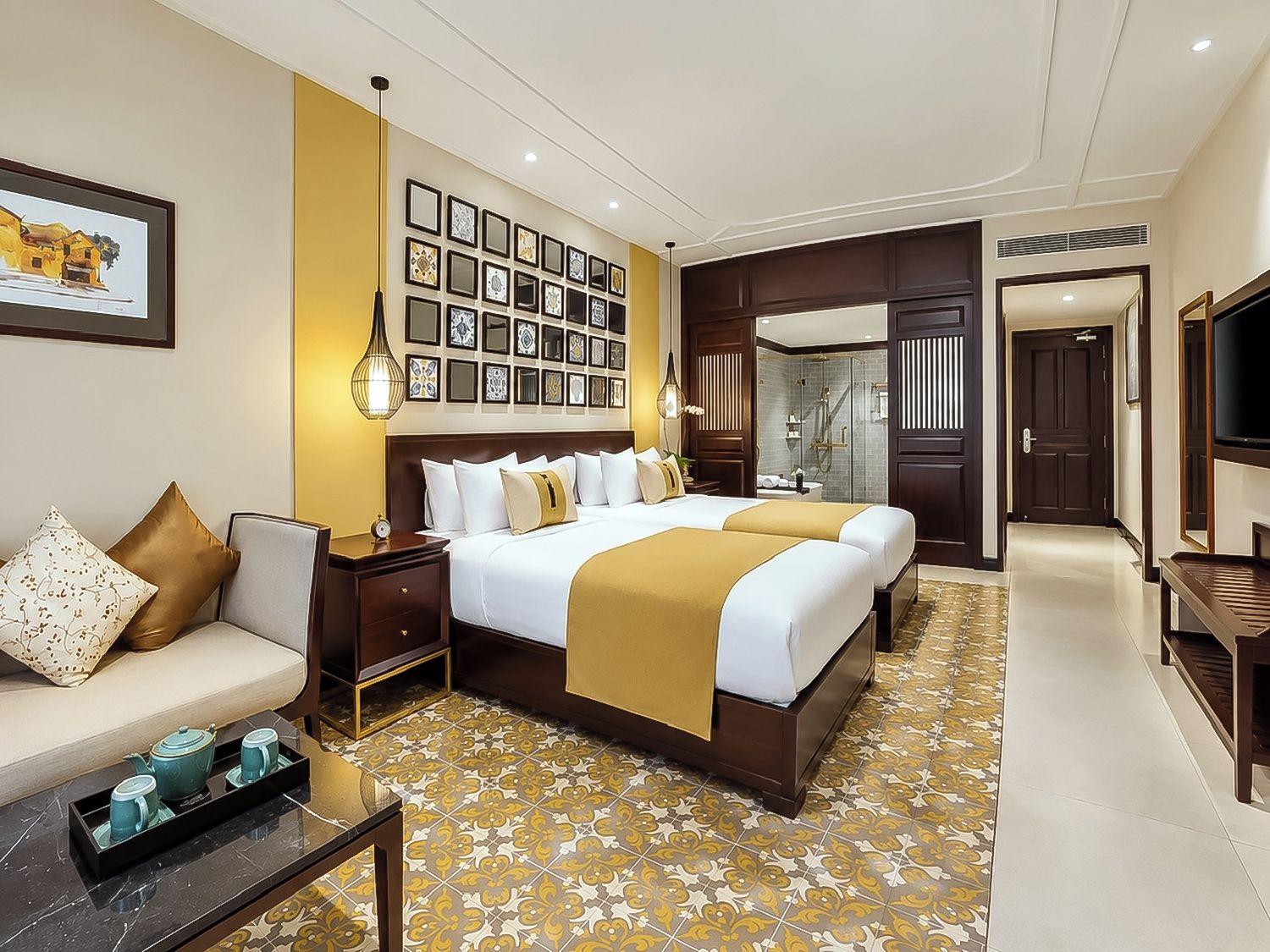 Quarto de hotel com uma cama grande, um sofá, uma mesa de centro e uma parede decorada com quadros.
