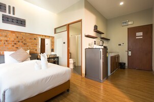 Quarto de hotel com cama, escrivaninha, frigorífico e banheiro.
