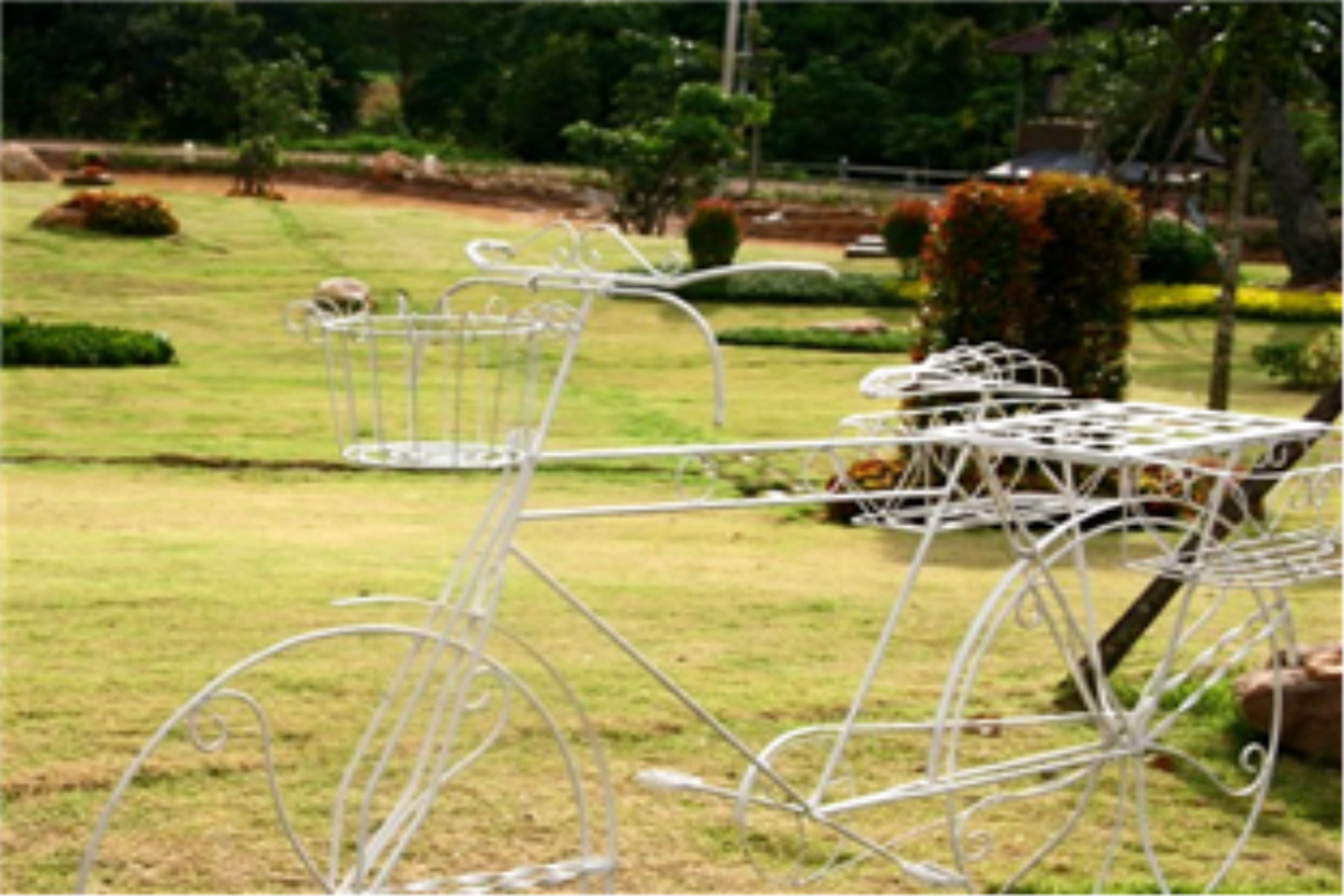 Um jardim com um banco de metal branco e uma mesa pequena.