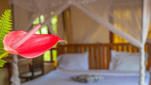 Uma cama com dossel, cabeceira de madeira e cobreleira branca.