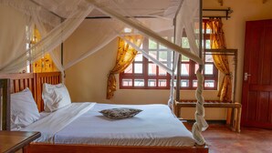 Uma cama com dossel, roupa de cama branca e almofada decorativa.