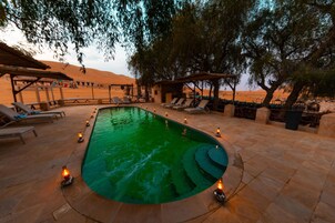 Uma área de piscina com espreguiçadeiras e um pérgola.