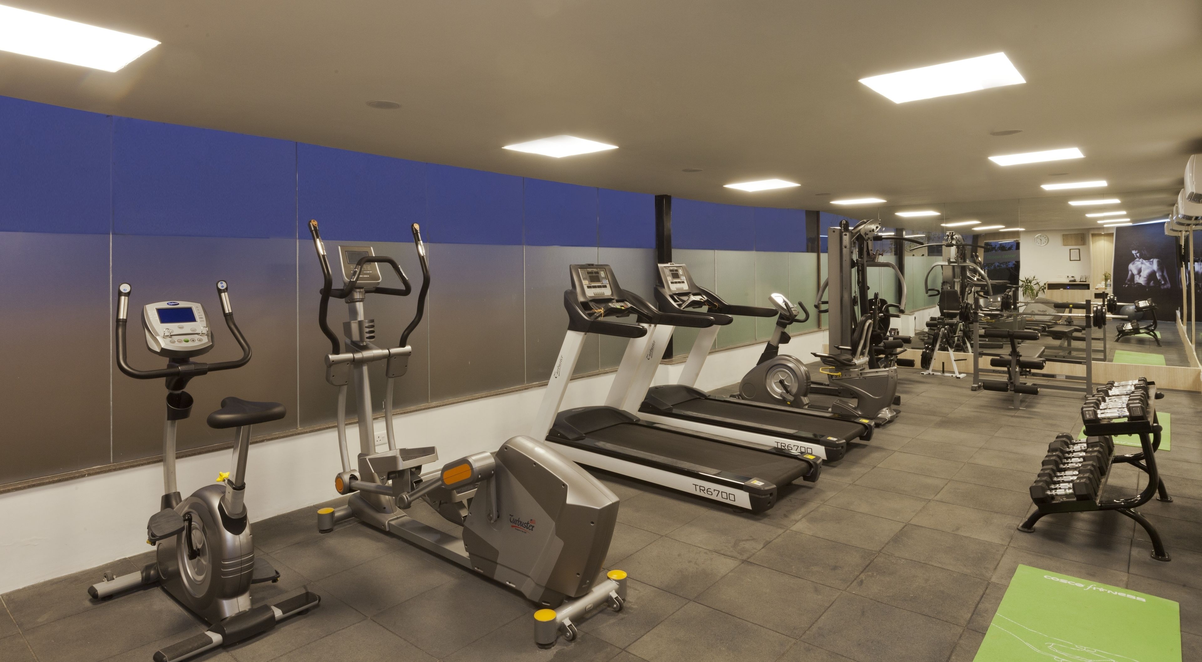 Uma academia com diversos equipamentos de exercícios, incluindo esteiras e bicicletas ergométricas, dispostos em fileiras.