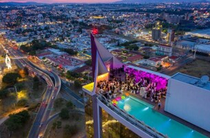 Hotel alto com piscina no terraço e vista panorâmica da cidade.