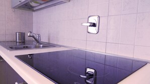 Uma cozinha com uma pia de aço inoxidável, uma torneira e um micro-ondas.