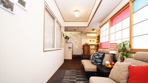 Sala de estar com sofá, uma mesinha com uma planta e vista para a cozinha.