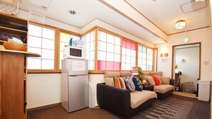 Uma sala de estar aconchegante com um sofá, micro-ondas e geladeira.