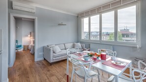Uma sala de estar moderna com área de jantar, janelas amplas e vista para a cidade.