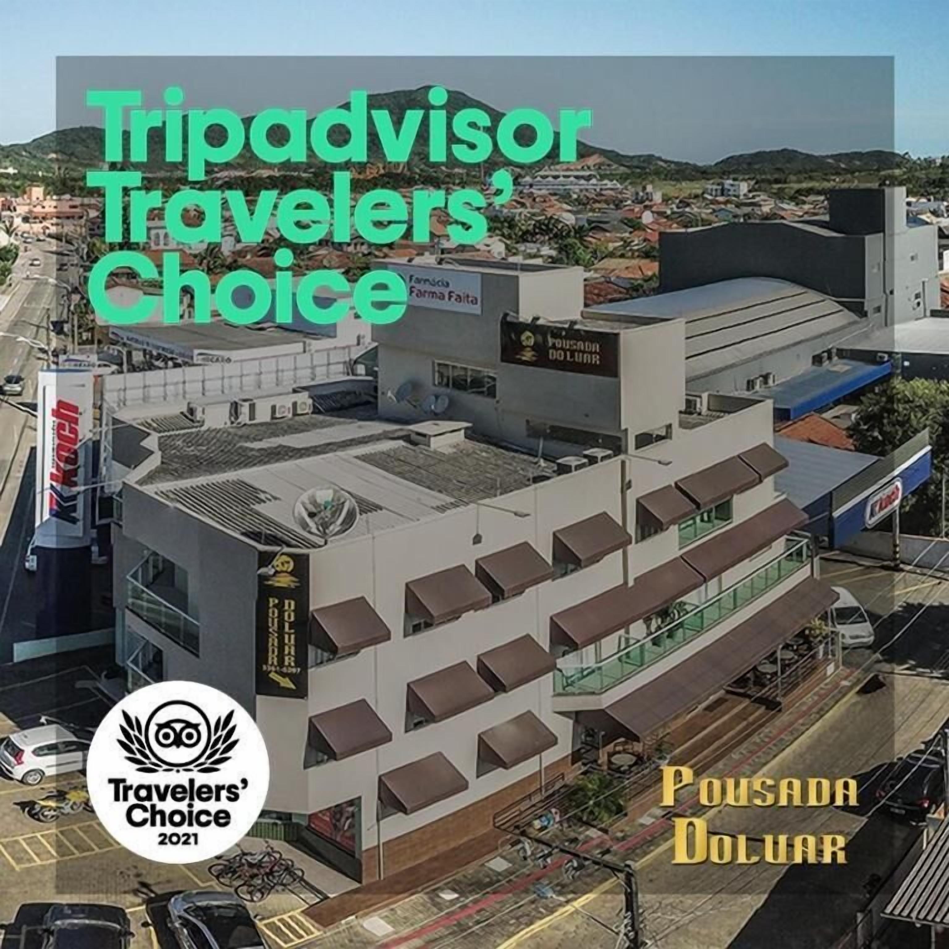 Um edifício com várias varandas, uma placa com a inscrição 'Pousada Doluar' e um prêmio 'Escolha dos Viajantes 2021'.