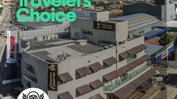 Um edifício com várias varandas, uma placa com a inscrição 'Pousada Doluar' e um prêmio 'Escolha dos Viajantes 2021'.