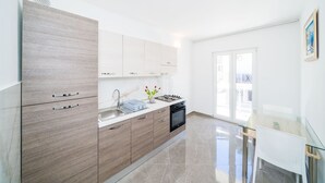 Uma cozinha moderna com bancada de mármore, eletrodomésticos de aço inoxidável e mesa de jantar de vidro.