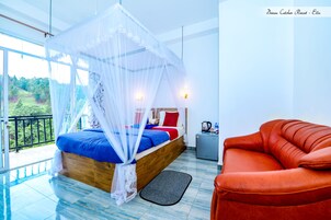 Quarto com cama sob dossel, sofá vermelho e vista para o verde lá fora.