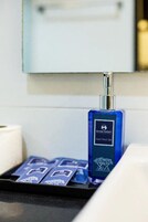 Casa de banho com um dispensador de gel de lavagem para as mãos azul, uma pia branca e um espelho sobre a pia.
