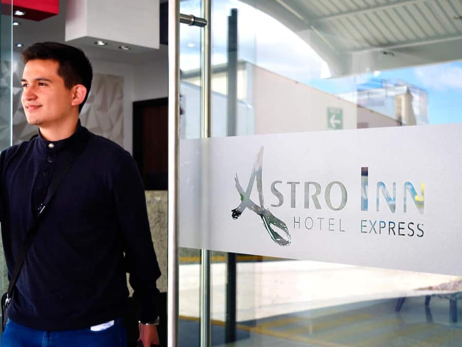 Um homem em frente a uma placa indicando o Hotel Astro Inn Express.