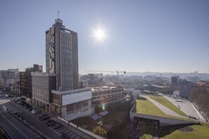 Um edifício alto com design moderno, rodeado por outros edifícios e um céu limpo.