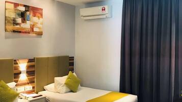 Quarto de hotel com duas camas, ar condicionado na parede, um quadro e piso xadrez.