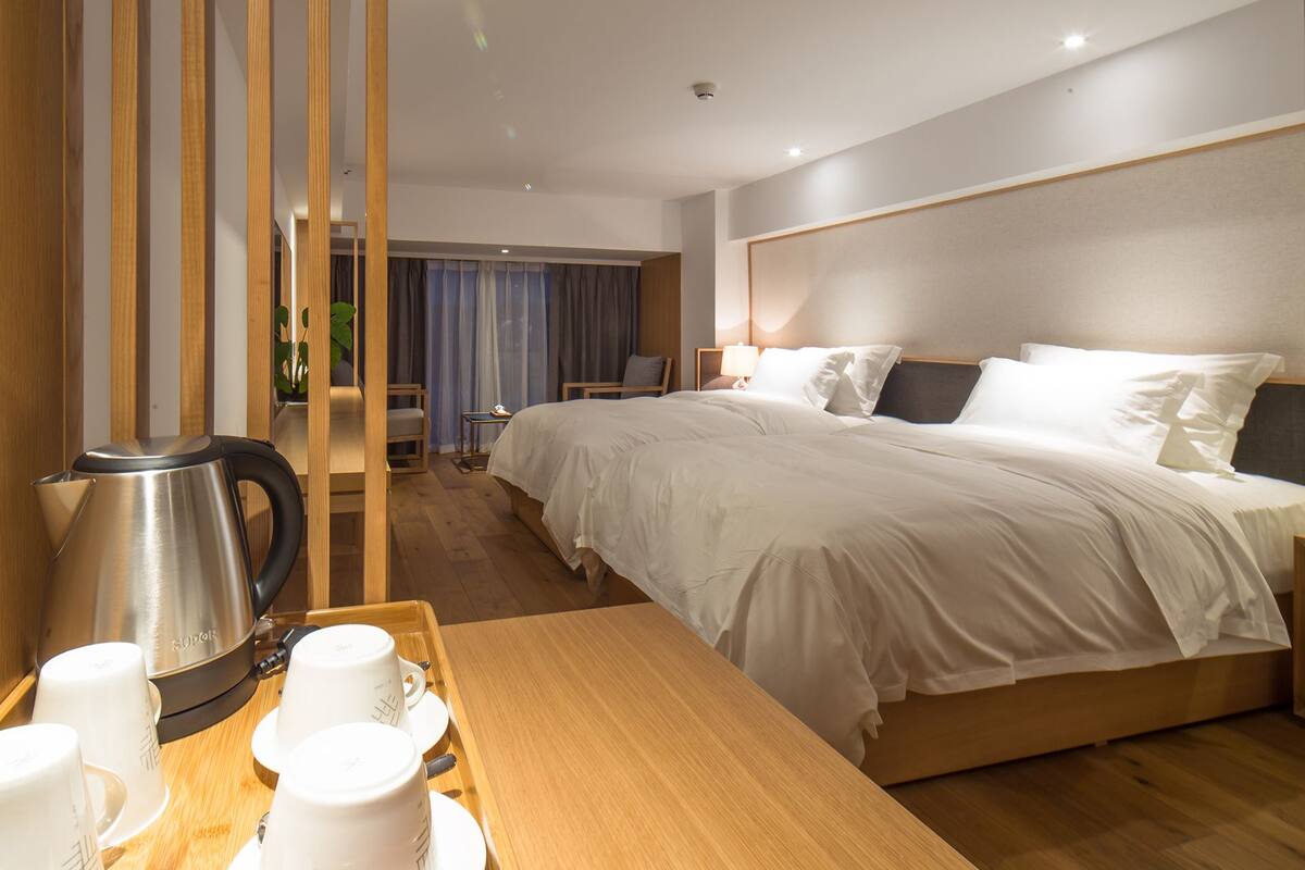 Quarto de hotel com cama, mesa de cabeceira e divisória de madeira.