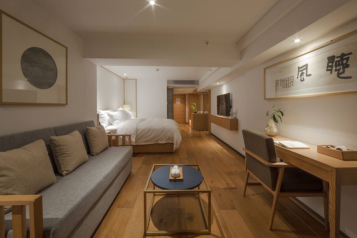 Quarto de hotel moderno com sofá, cama, escrivaninha e televisão.