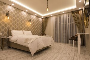 Quarto moderno com cama grande, mesas de cabeceira e uma pequena mesa.