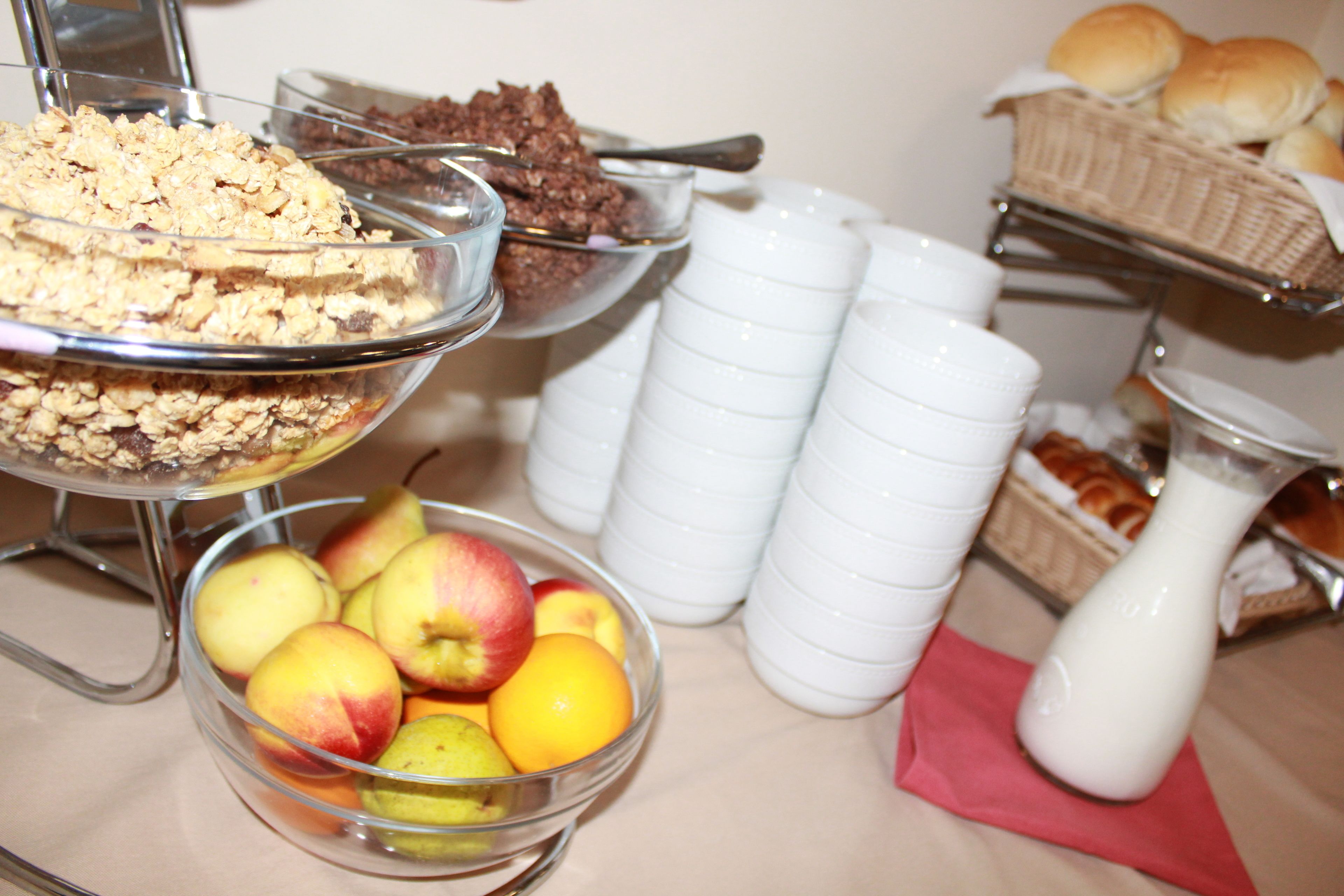 Buffet com diversas opções de comida, incluindo frutas, cereais e doces.