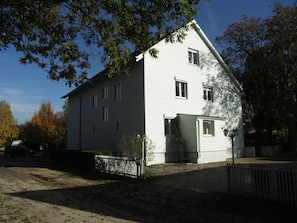 Um edifício branco de dois andares, com várias janelas, um pequeno alpendre e um quintal cercado.