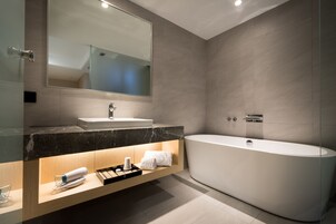 Uma casa de banho moderna com uma banheira independente, um espelho grande e uma toucador com bancada de mármore.