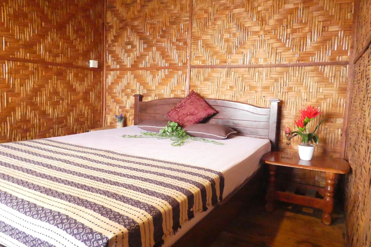 Um quarto com uma cama, mesa de cabeceira e um painel de parede trançado.
