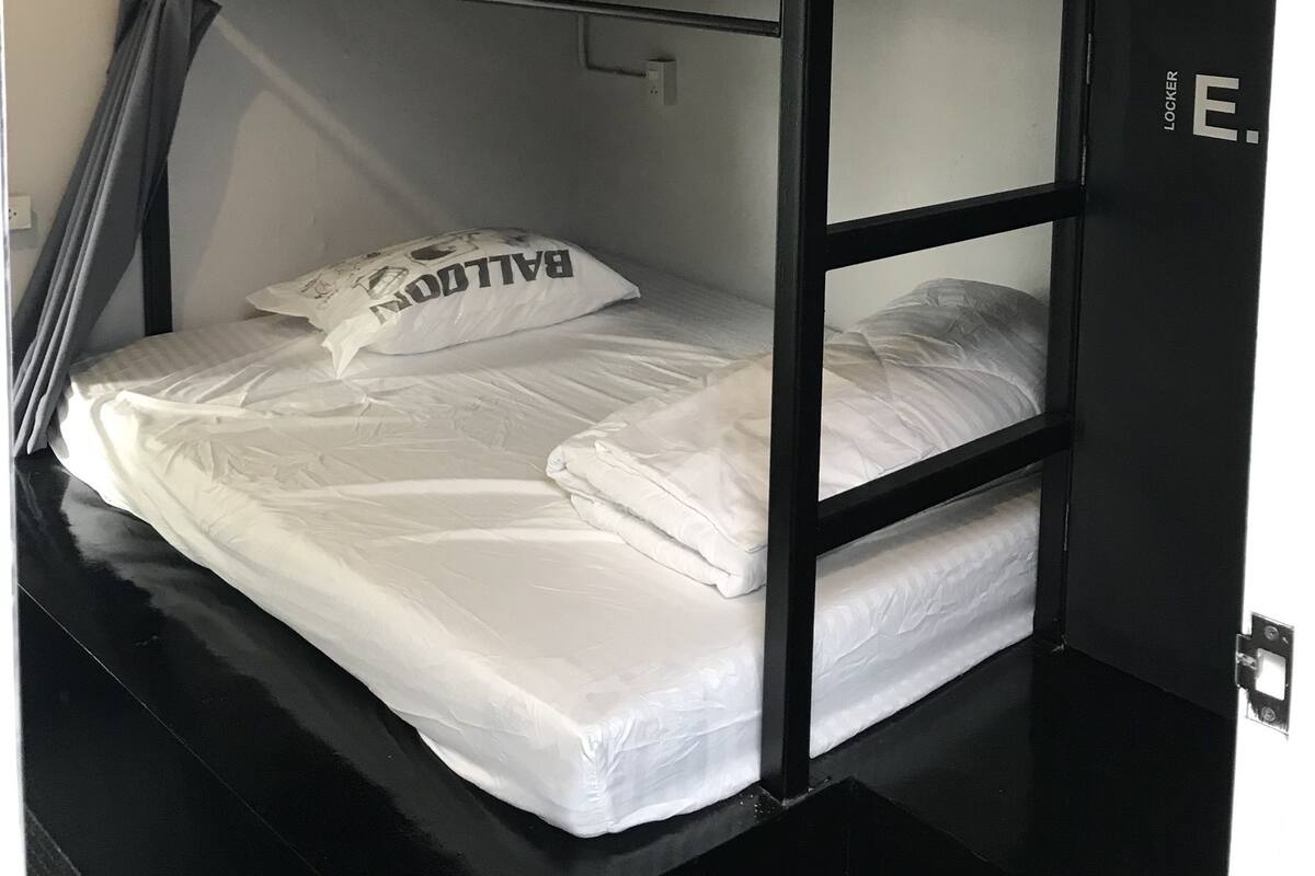 Uma cama beliche com colchão identificado como "BALLONG" e estrutura de metal preto.