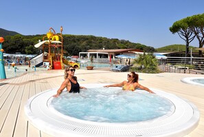 Área de hidromassagem em um convés de navio de cruzeiro, com um toboágua e piscina ao fundo.