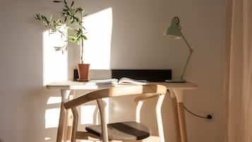 Um espaço de trabalho com escrivaninha, cadeira, planta em vaso e abajur.