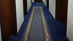 Um corredor com carpete estampado, portas de madeira e teto com iluminação embutida.