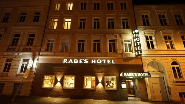 Hotel Rabe com letreiros iluminados, várias janelas e estilo arquitetônico clássico.