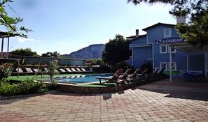 Uma área de piscina com espreguiçadeiras e um edifício com a inscrição 'GÜRKAN'.