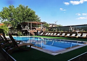 Piscina com espreguiçadeiras e área coberta.