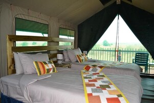 Cama de casal com colcha, cabeceira de madeira e mesa de cabeceira com abajur.