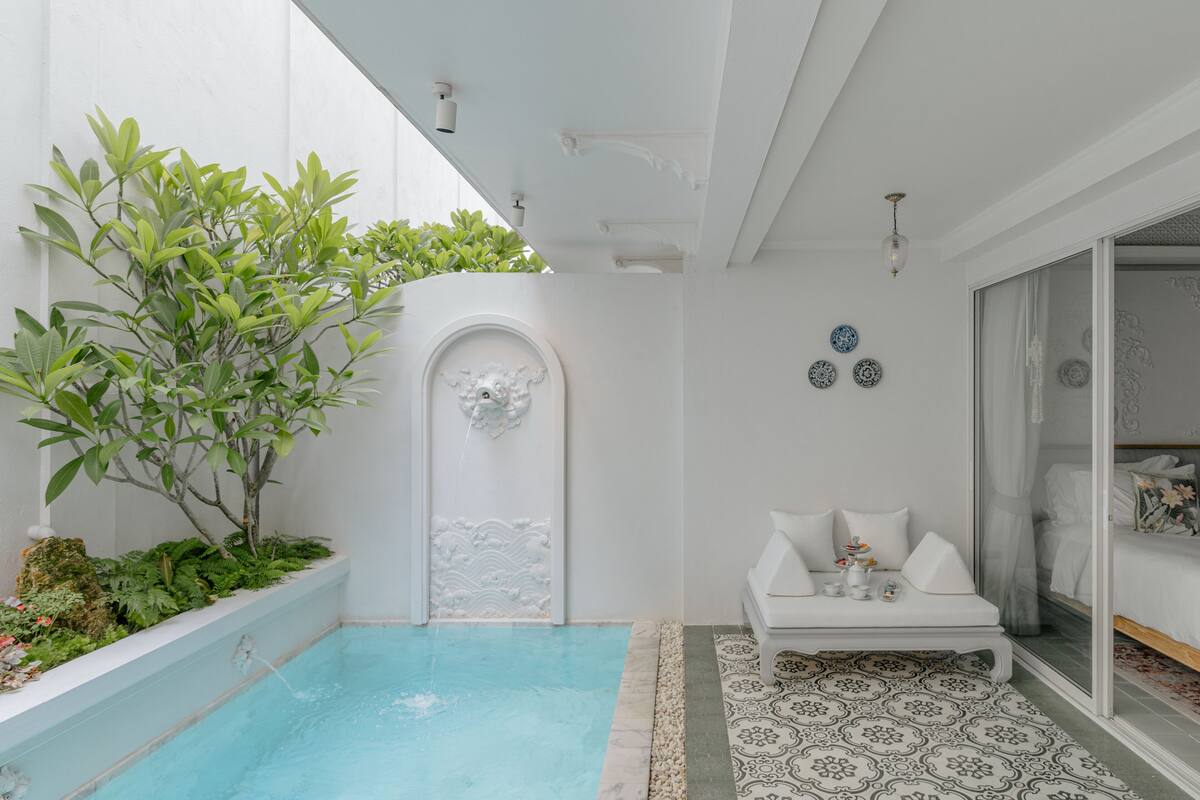 Um banheiro moderno com uma pequena piscina, um banco branco e pratos decorativos na parede.