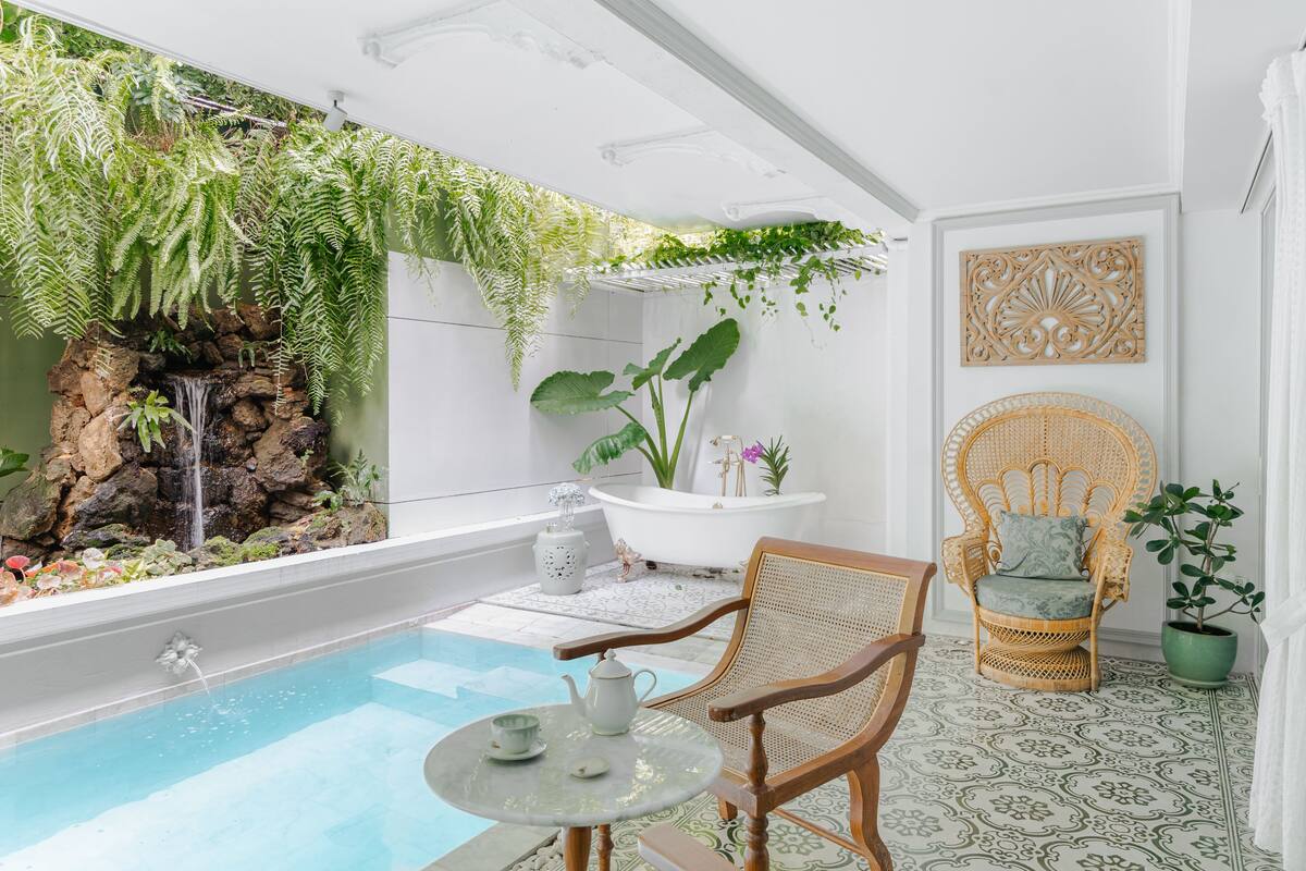 Uma área de piscina interior tranquila, com uma cascata, assentos e vegetação exuberante.