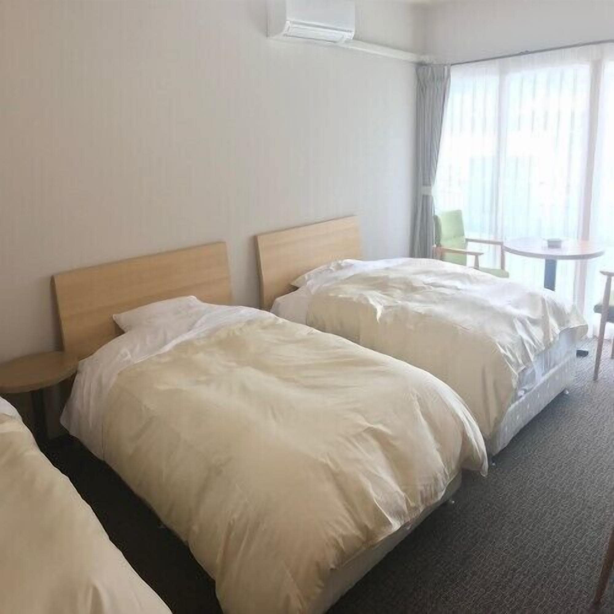 Quarto de hotel com duas camas, uma mesinha e uma cadeira.
