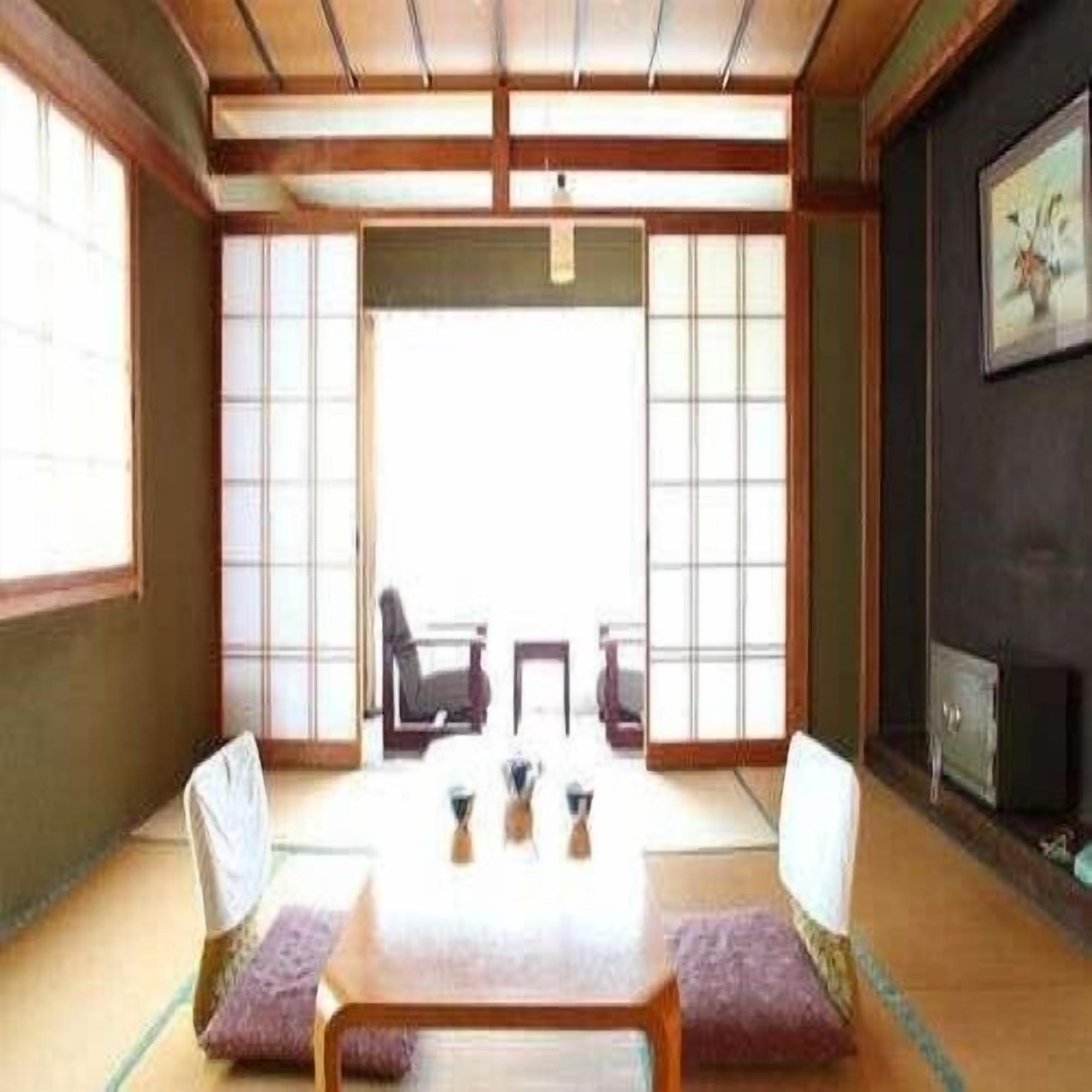 Um quarto japonês tradicional com piso de tatame, uma mesa baixa com almofadas e portas deslizantes.