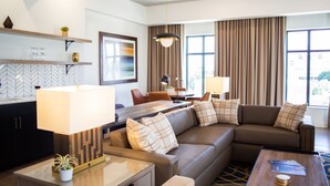 Uma sala de estar moderna com sofá, mesa de centro e área de jantar com mesa e cadeiras.