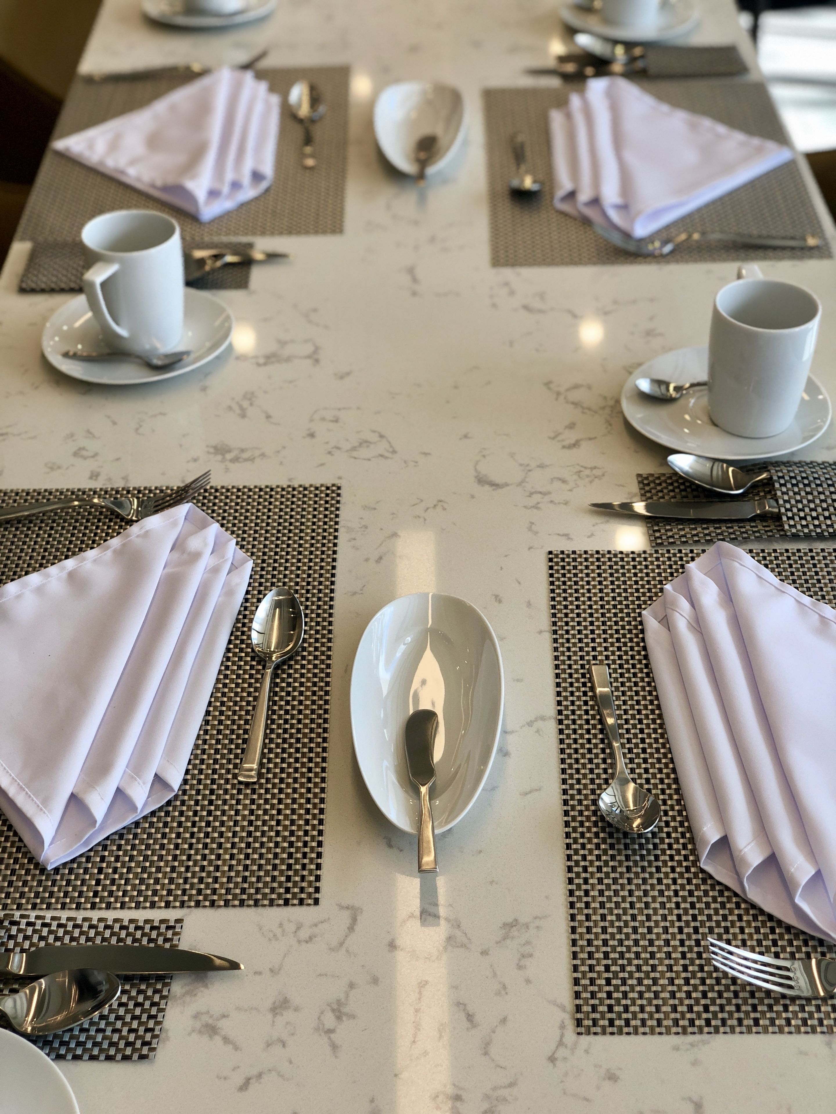 Uma mesa posta para refeição, com pratos, talheres e guardanapos.