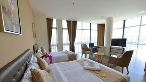 Quarto de hotel com duas camas, uma televisão, uma escrivaninha e uma cadeira.