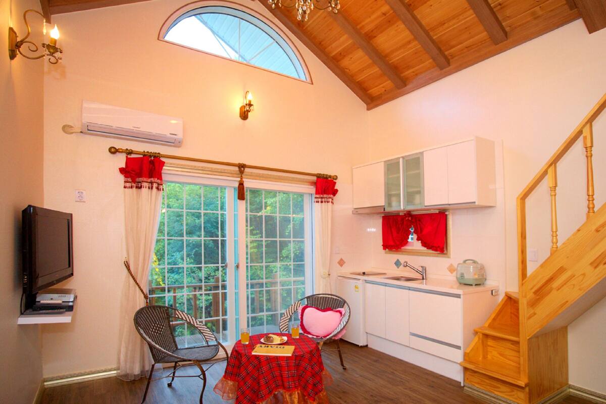 Um quarto aconchegante com uma mesa de jantar, cadeiras, televisão e uma cozinha.