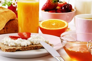 Disposição para o pequeno-almoço com torradas, cream cheese, morangos, sumo de laranja e chá.