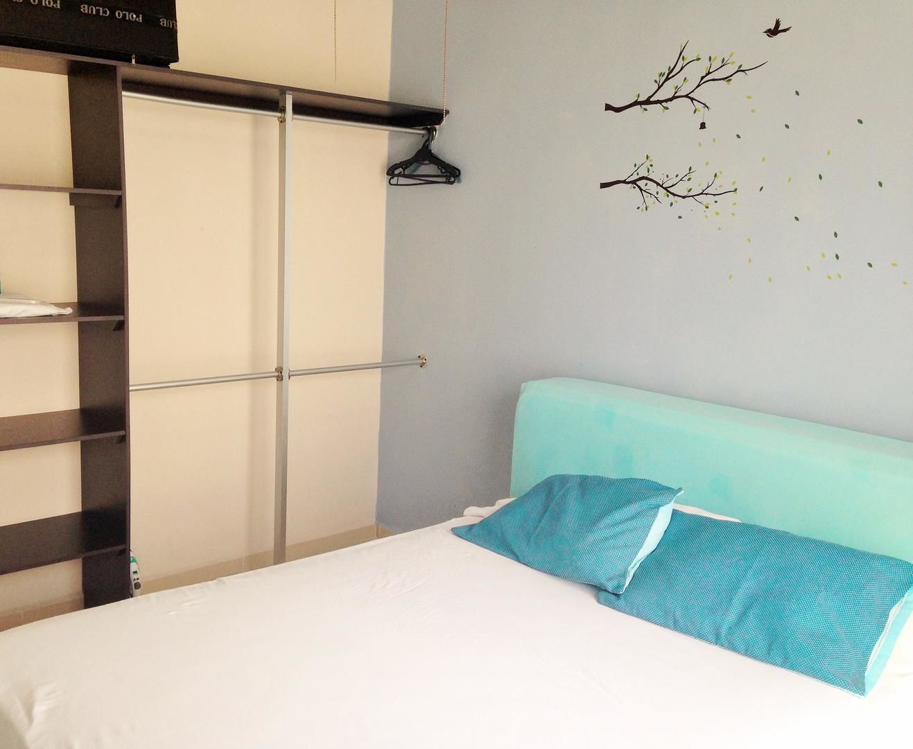 Quarto com cama, guarda-roupa e um adorno na parede.